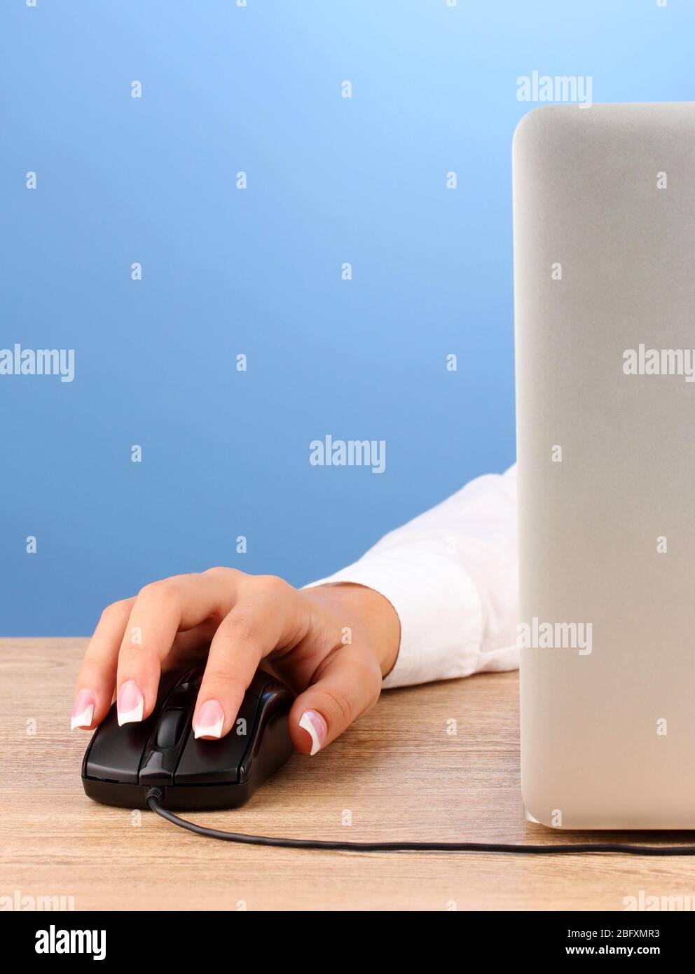 woman's hands pushing keys of pc mouse, on blue background close-up ...