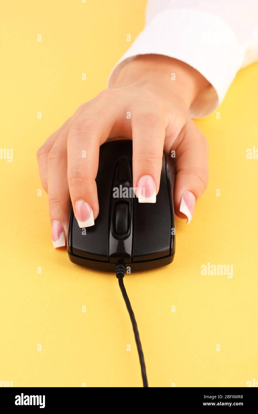 woman's hands pushing keys of pc mouse, on yellow background close-up ...
