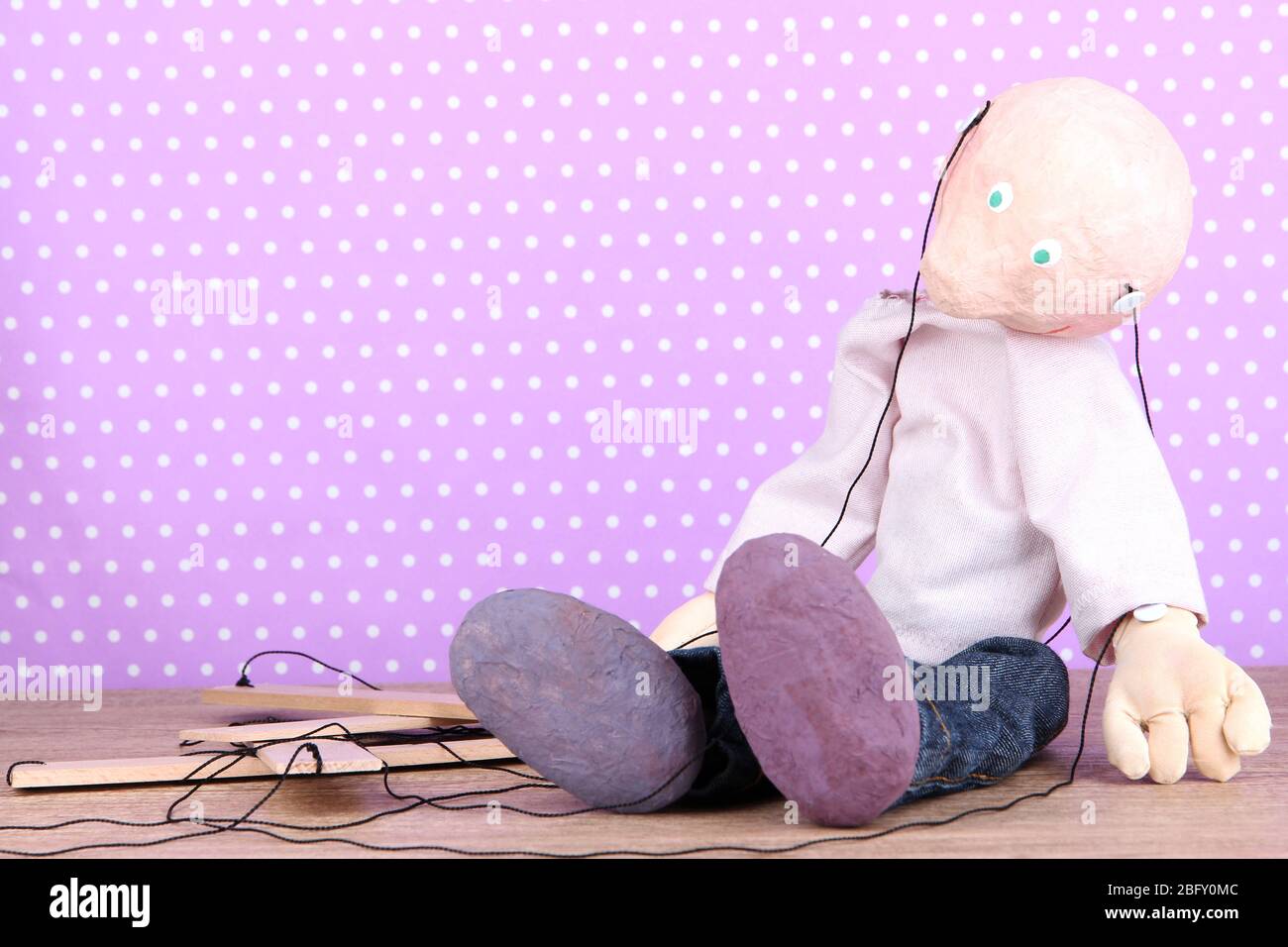 Wooden puppet sitting on polka dot background Stock Photo - Alamy