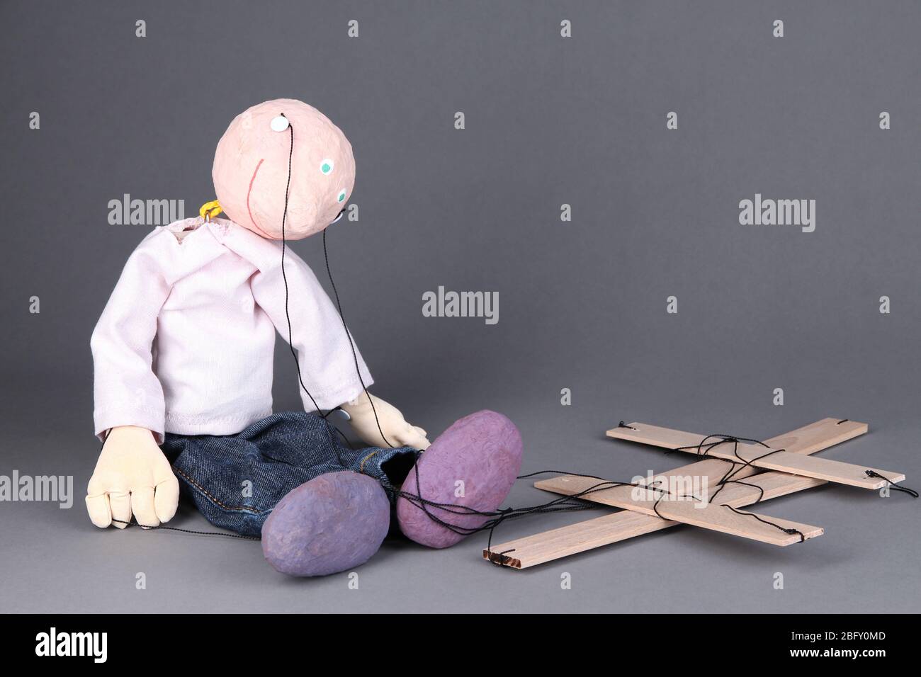 Wooden puppet sitting on grey background Stock Photo - Alamy