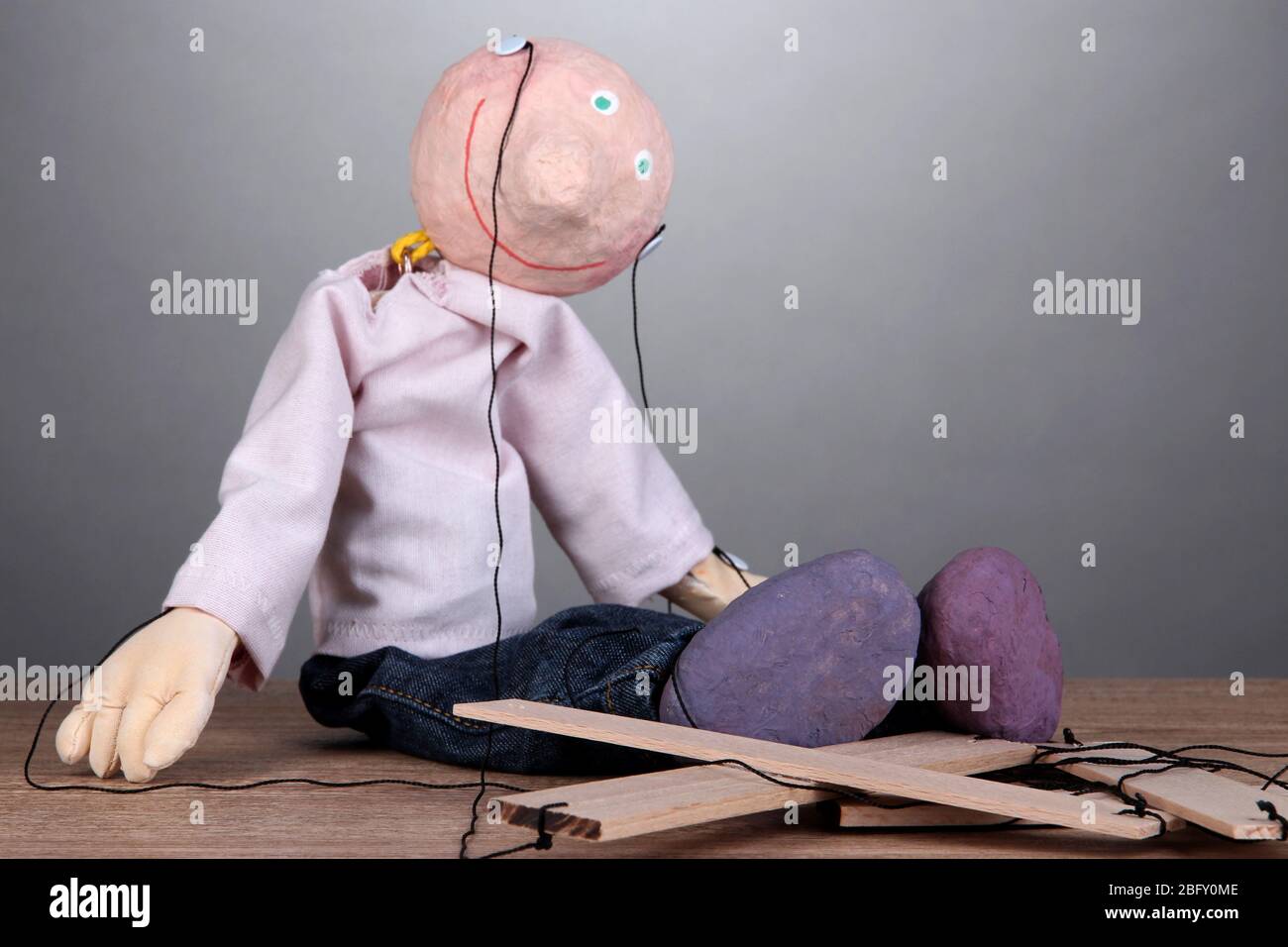 Wooden puppet sitting on grey background Stock Photo - Alamy