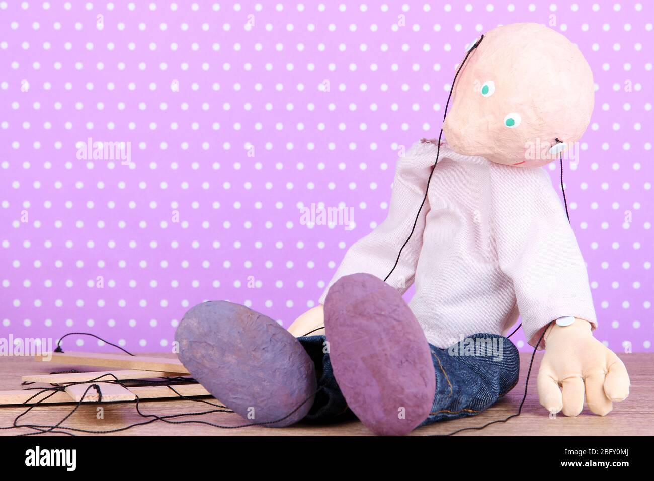 Wooden puppet sitting on polka dot background Stock Photo - Alamy
