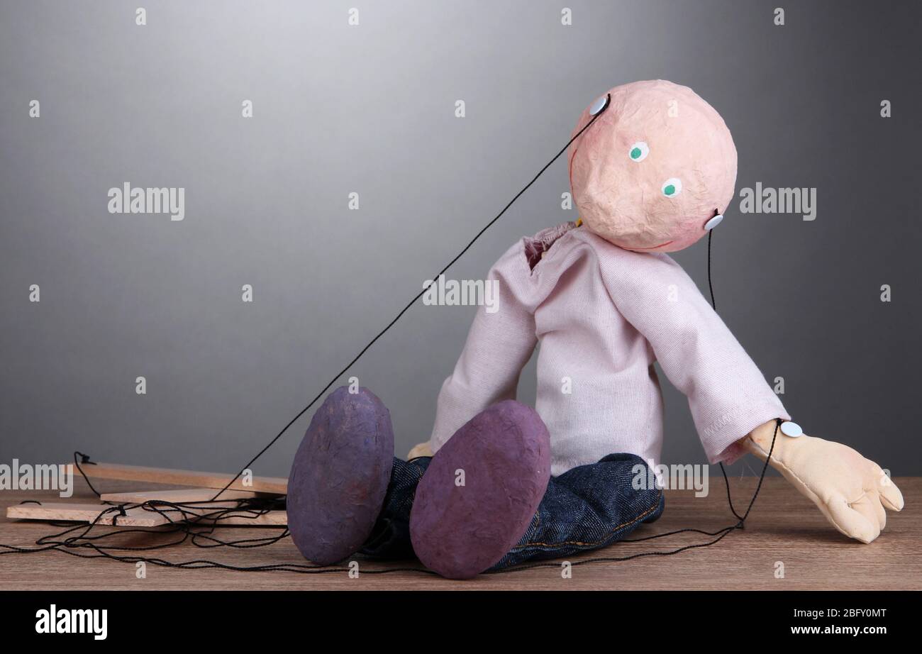 Wooden puppet sitting on grey background Stock Photo - Alamy
