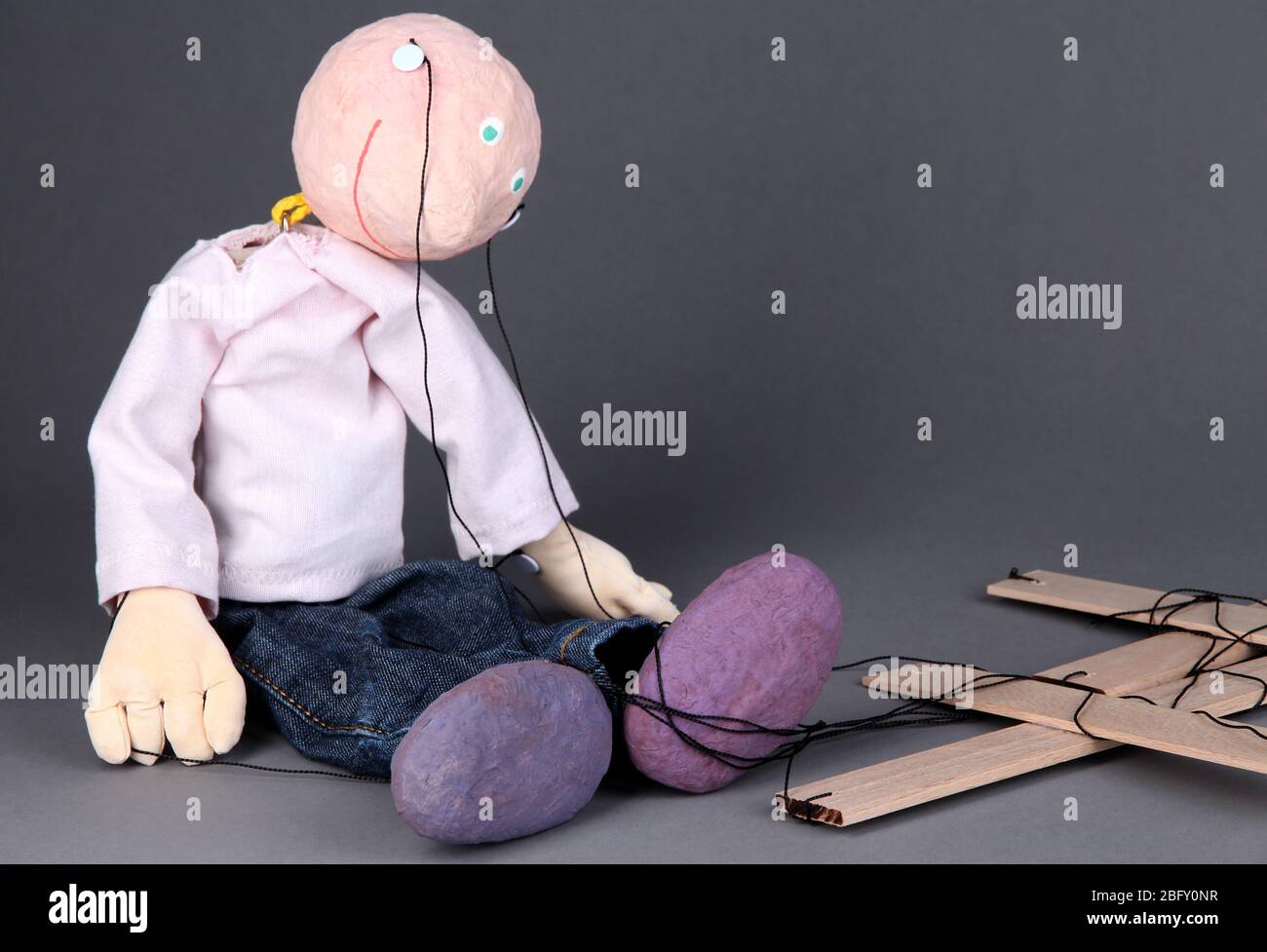 Wooden puppet sitting on grey background Stock Photo - Alamy