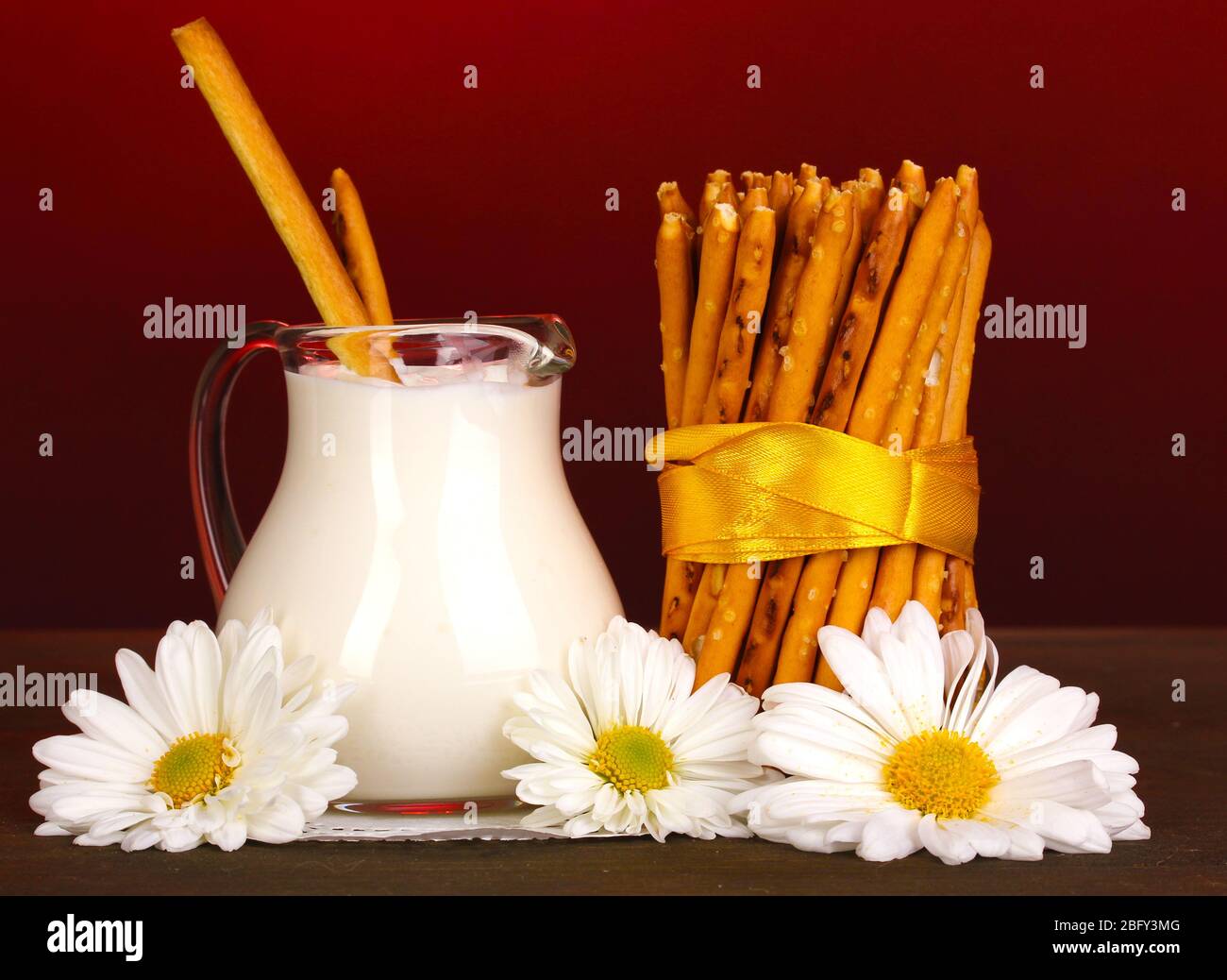 Tasty crispy sticks with pitcher with sour cream on wooden table on red ...