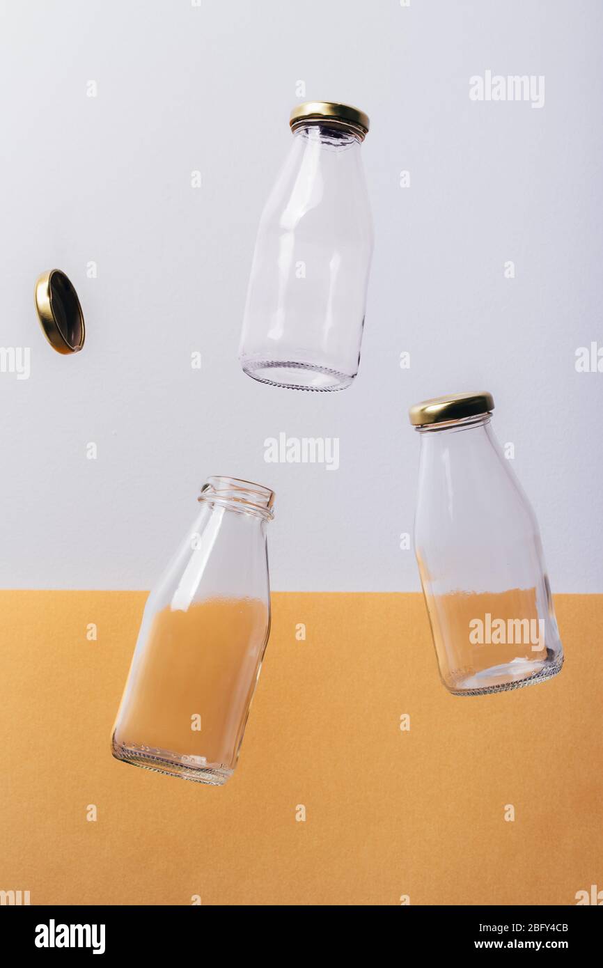 Glass bottles milk packaging falling down on white and orange ...