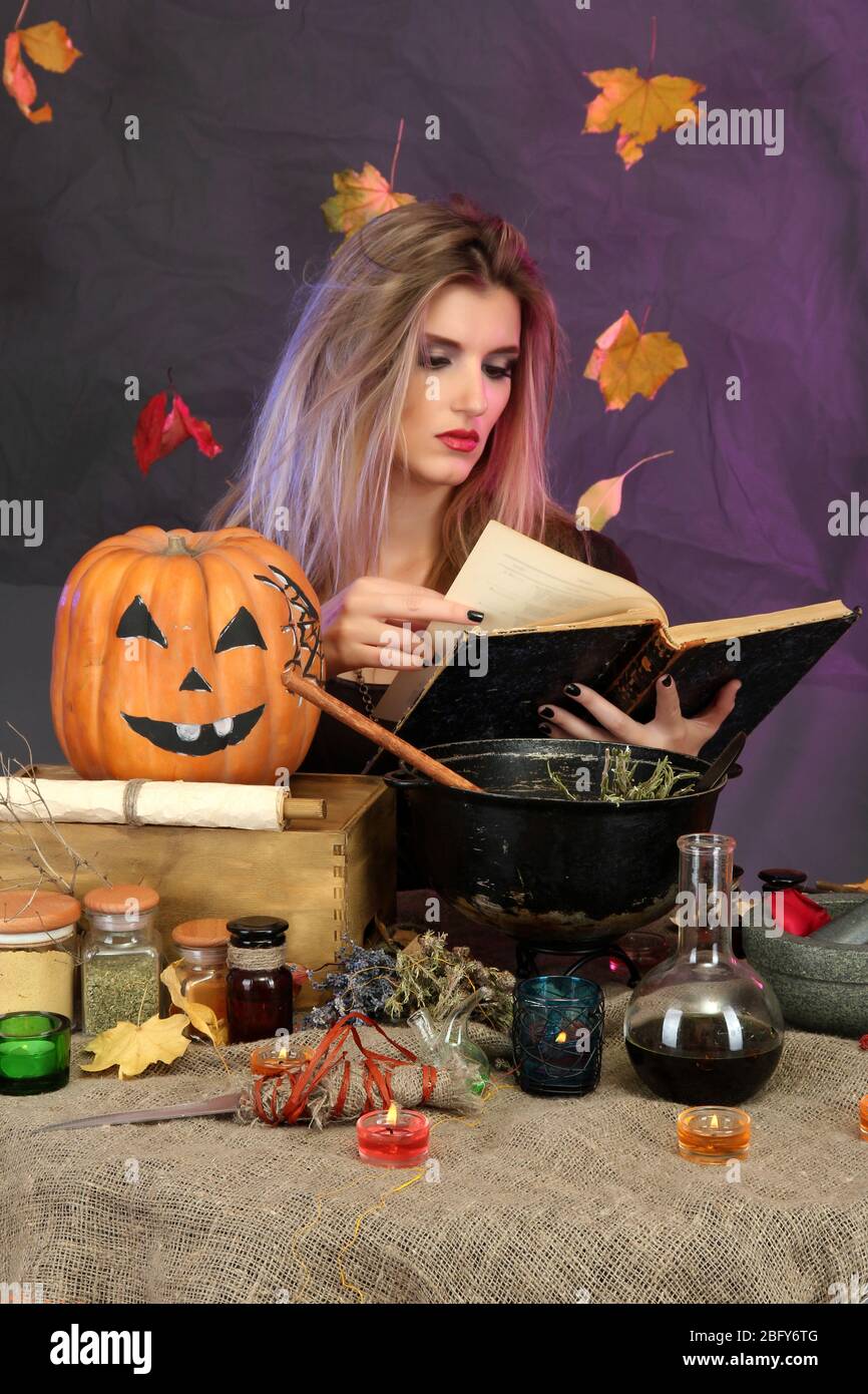 Halloween witch preparing poison soup in her cauldron on color ...