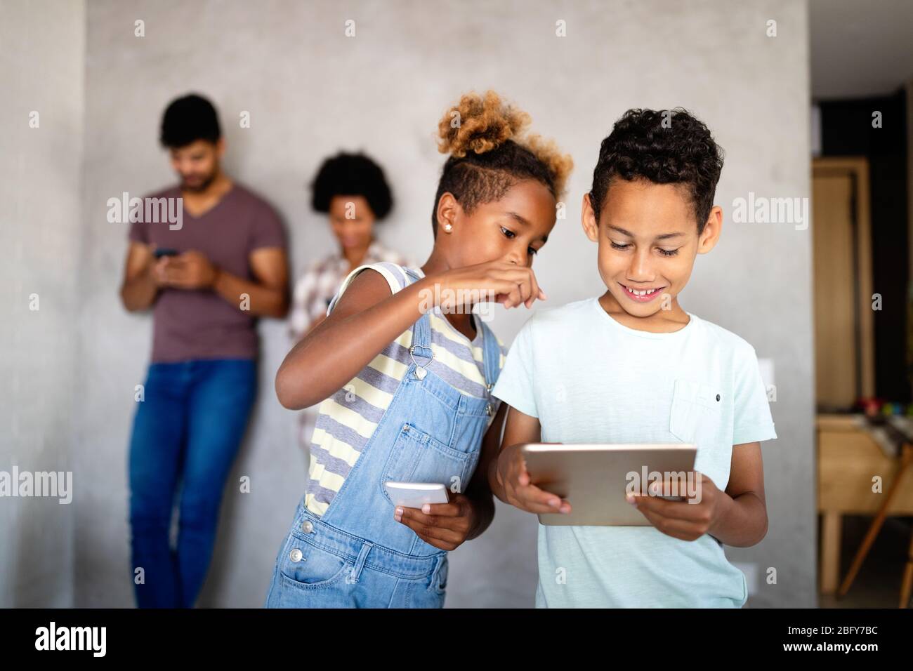 Happy african american family using technical devices, phone. tablet ...