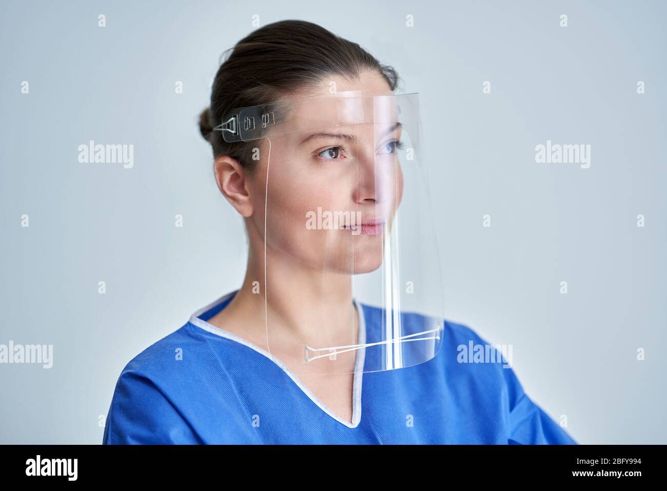 Close up portrait of female medical doctor or nurse wearing face shield ...