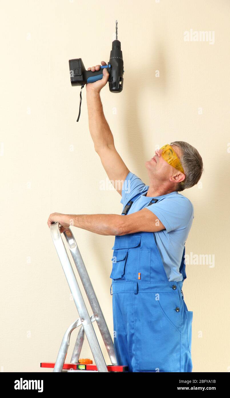 Handyman drill standing on ladder close-up Stock Photo - Alamy
