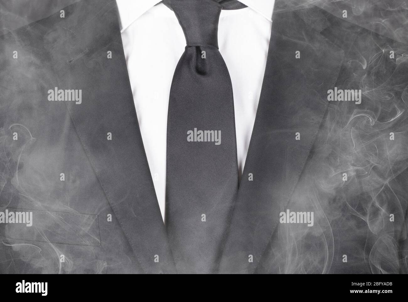 Man in a black suit and black tie, standing in smoke, close-up Stock ...