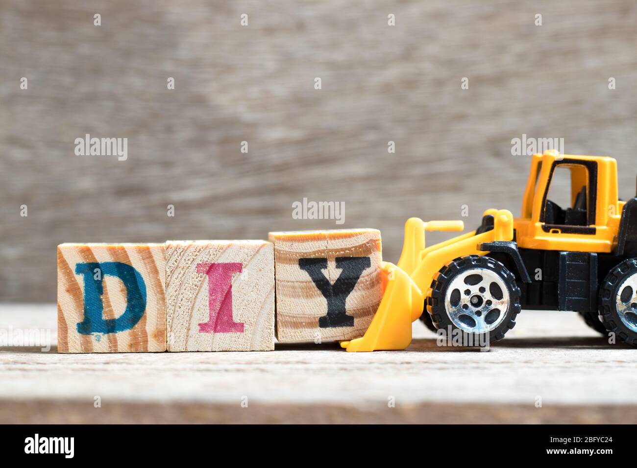 Toy bulldozer hold letter block Y to complete word DIY (abbreviation of ... Toy bulldozer hold letter block Y to complete word DIY (abbreviation of ...