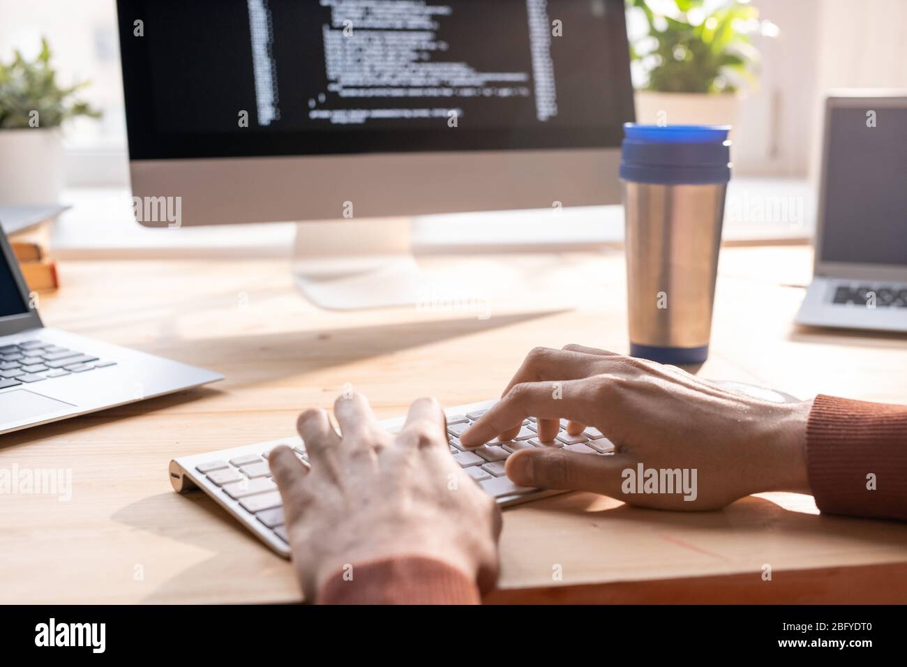 Close-up of unrecognizable programmer typing on keyboard while ...