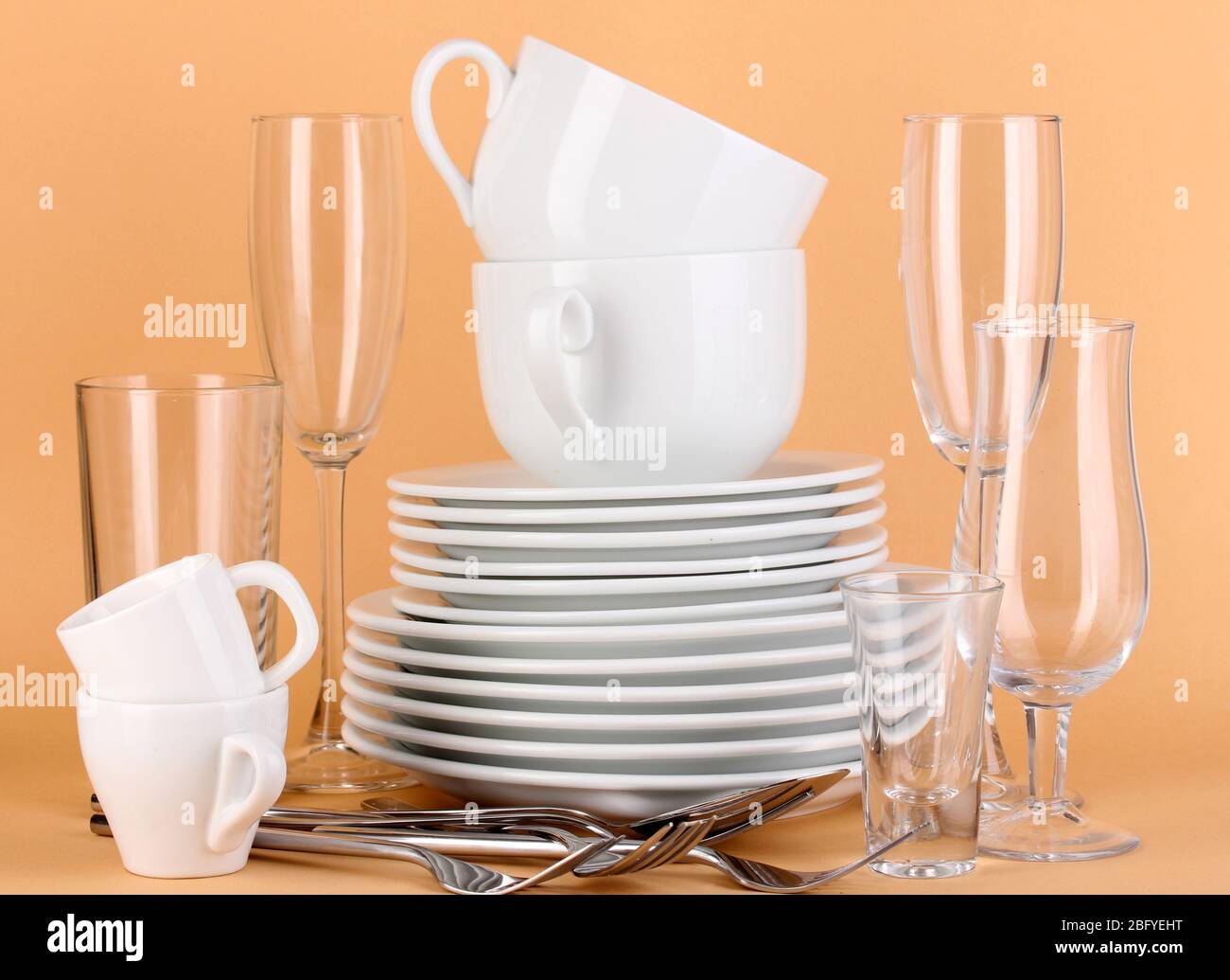 Clean white dishes on beige background Stock Photo - Alamy