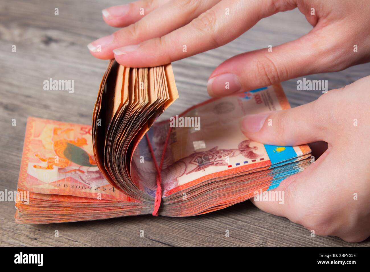 Hands holding a wad of money with an elastic band. Tenge KZT. National ...