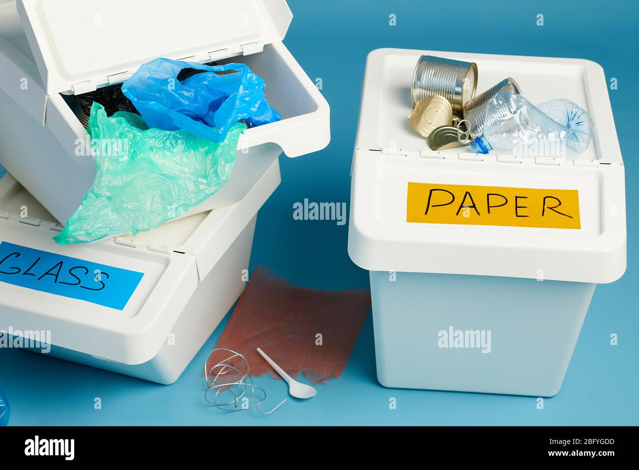 Close up of full trash bins for plastic and paper waste against blue ...
