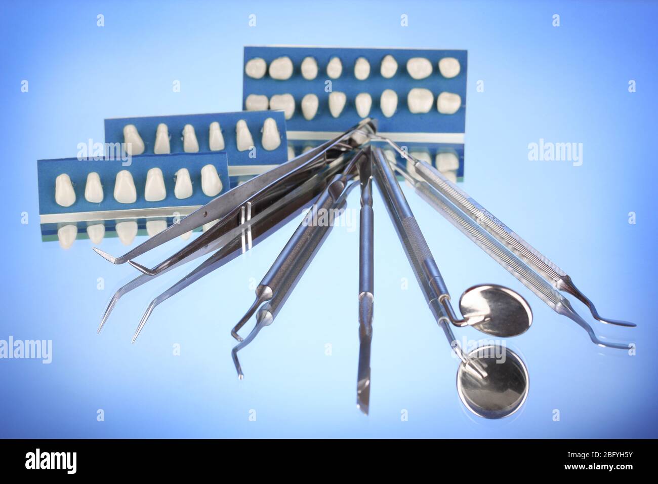 Set of dental tools with denture on blue background Stock Photo - Alamy