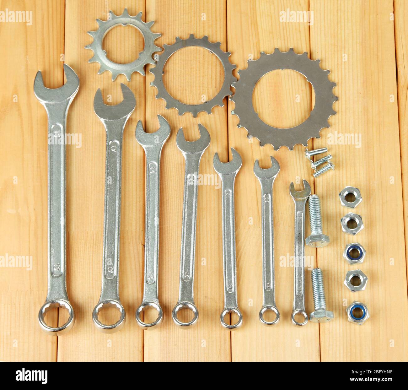 Machine gear, metal cogwheels, nuts and bolts on wooden background ...