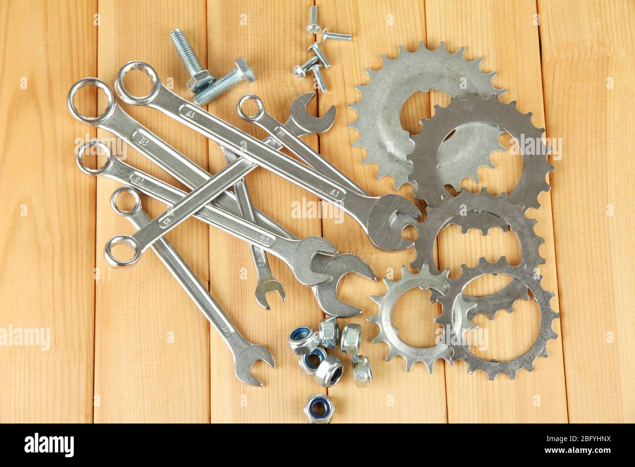 Machine gear, metal cogwheels, nuts and bolts on wooden background ...