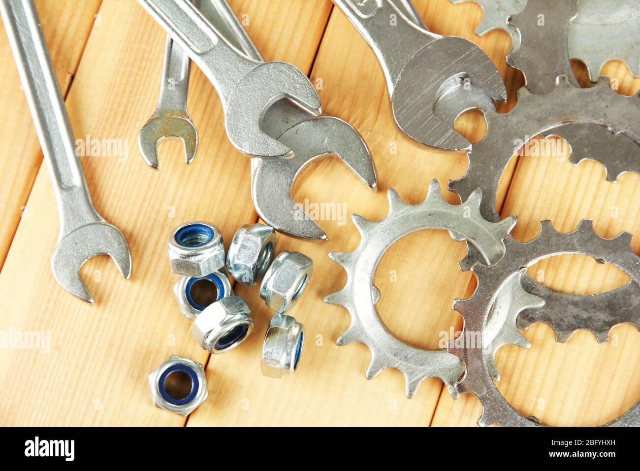 Machine gear, metal cogwheels, nuts and bolts on wooden background ...