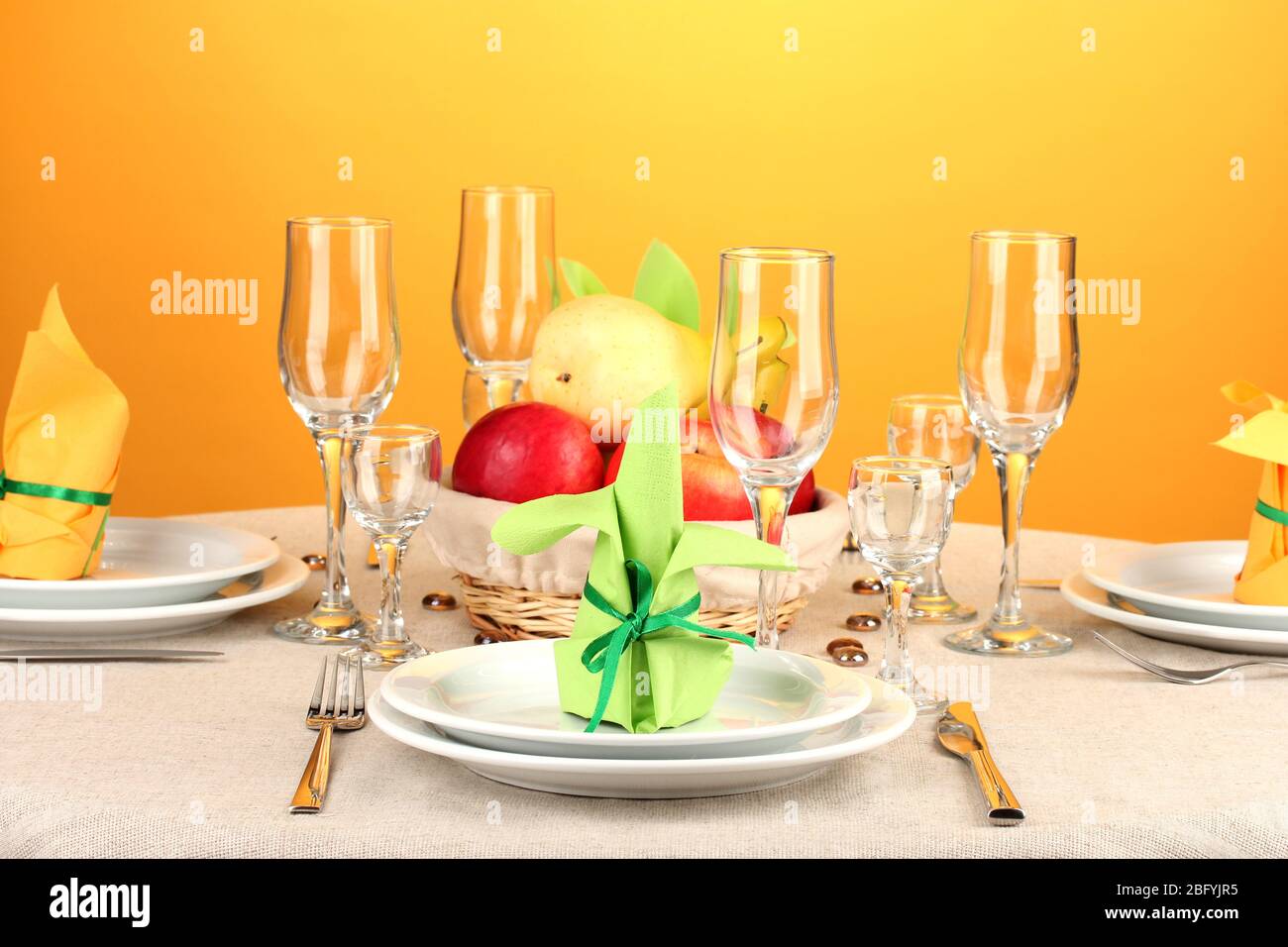 Table setting in green and yellow tones on color background Stock Photo ...