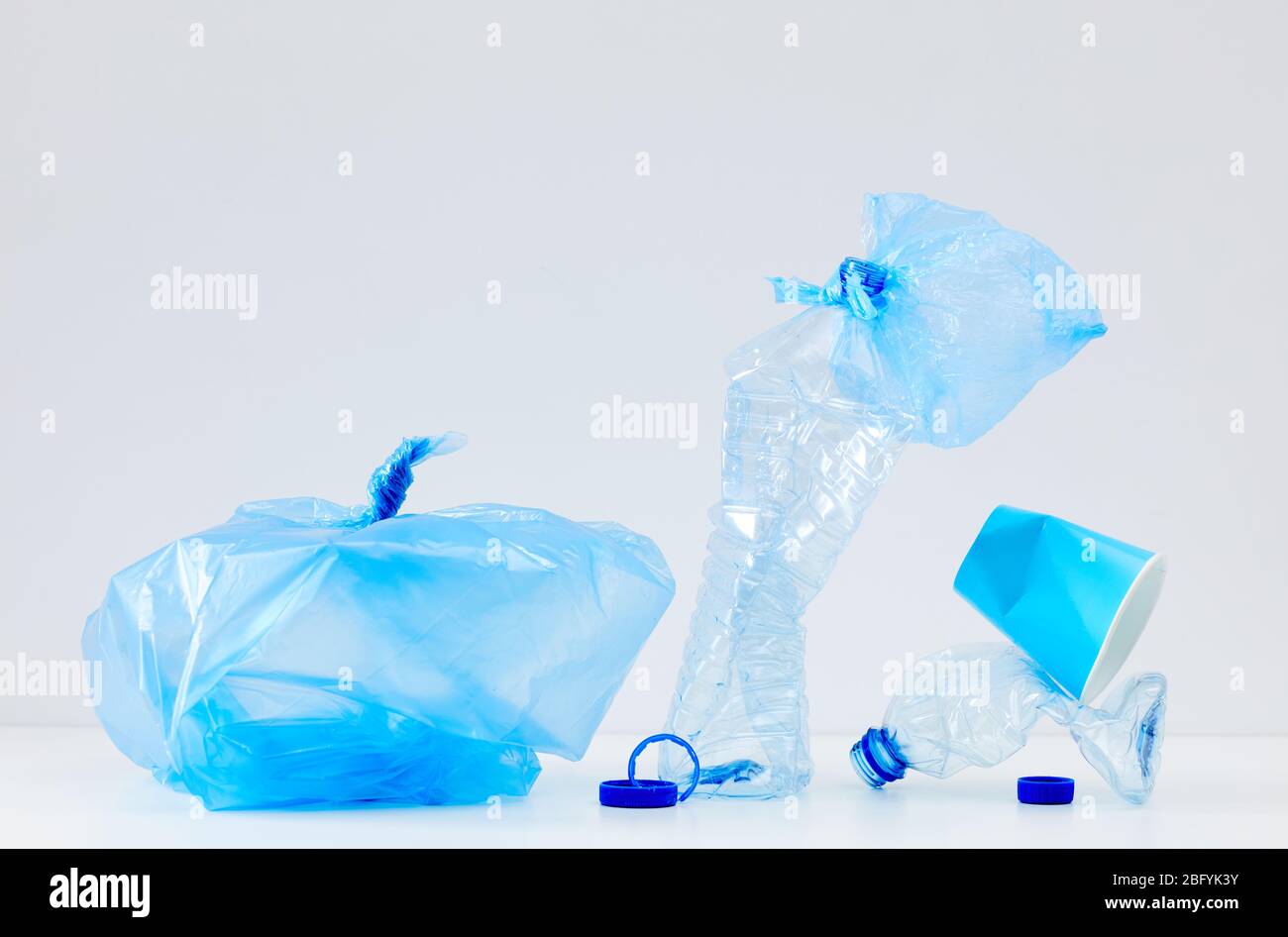 Minimal composition of discarded blue plastic items on white background ...