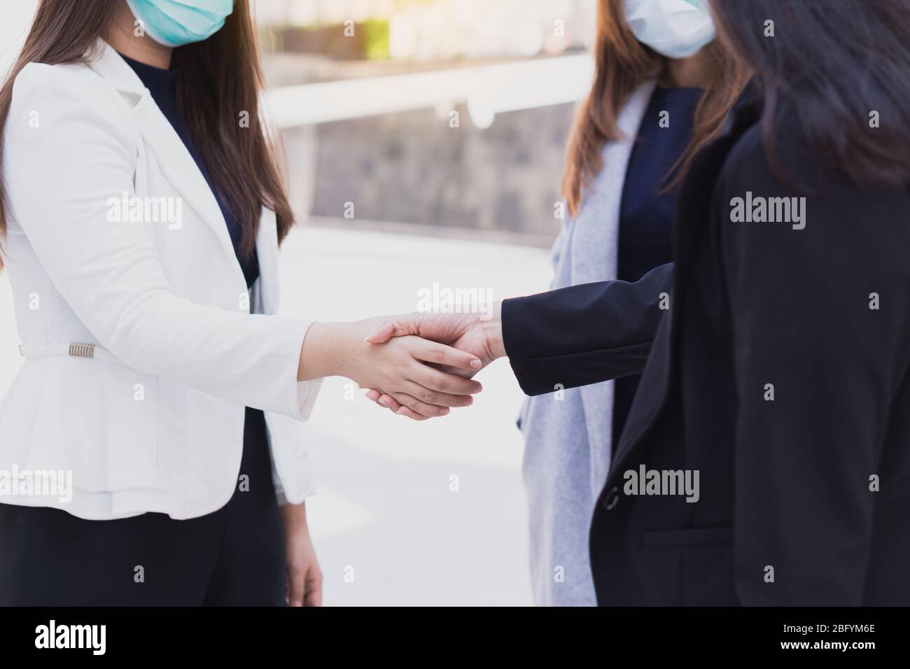 Two business woman wearing mask and making handshake in the city ...