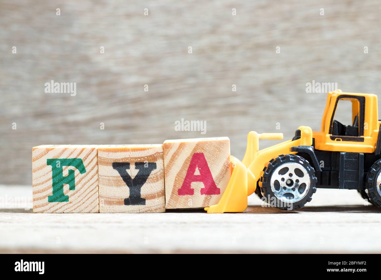 Toy bulldozer hold letter block A to complete word FYA (Abbreviation of ...