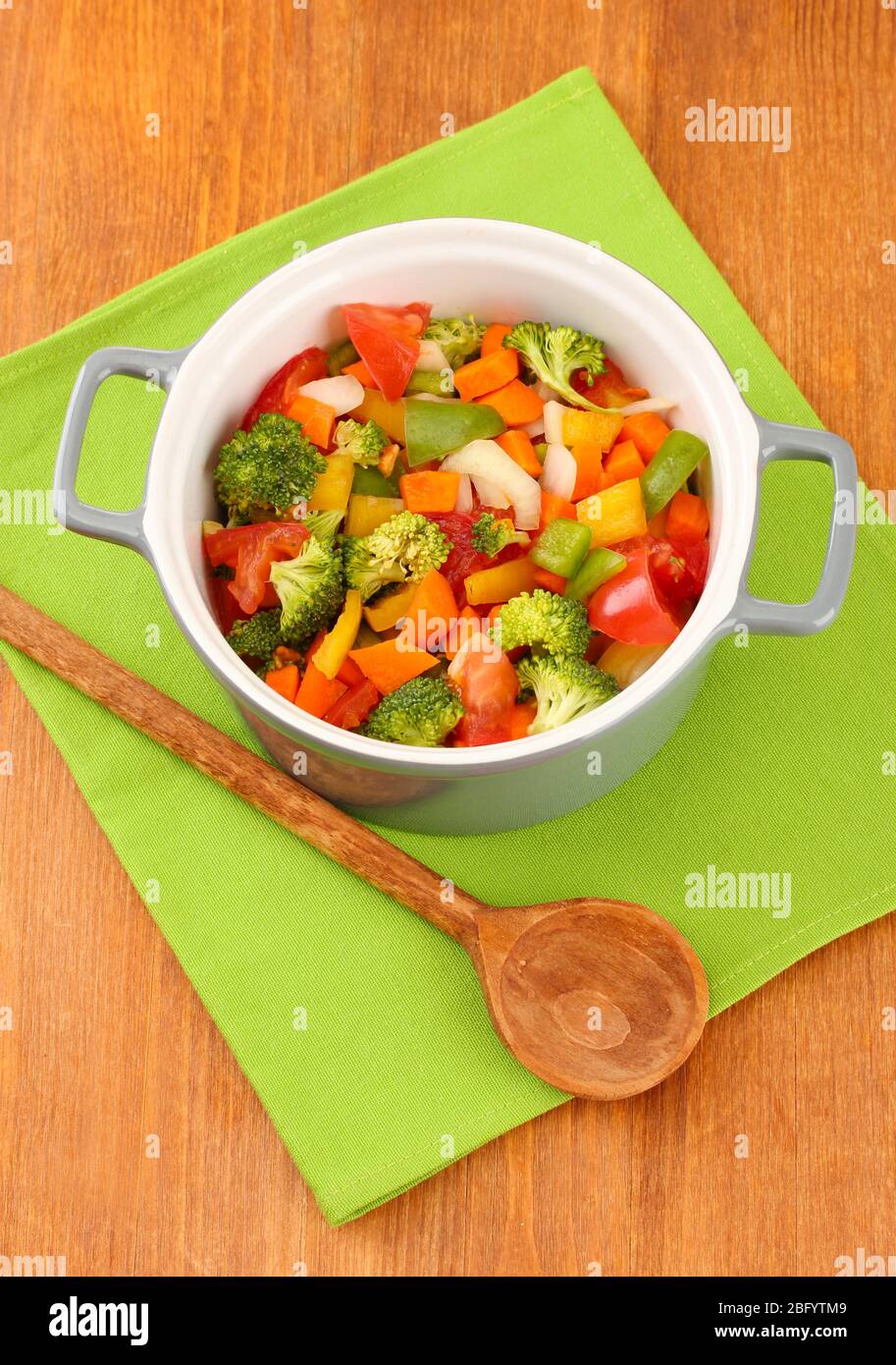 Vegetable stew in gray pot on color napkin on wooden background Stock ...