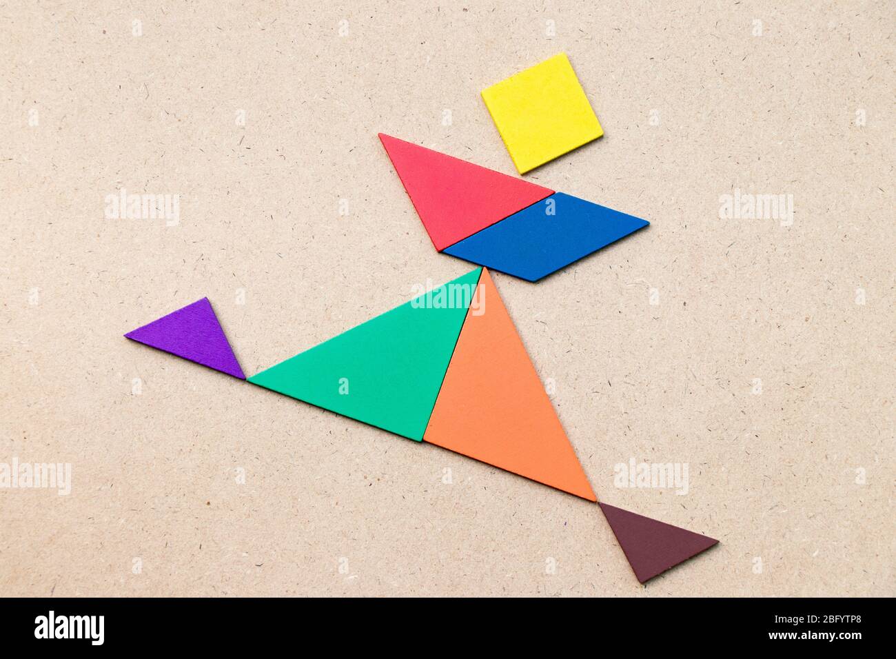 Color tangram in running man shape on wood background Stock Photo - Alamy