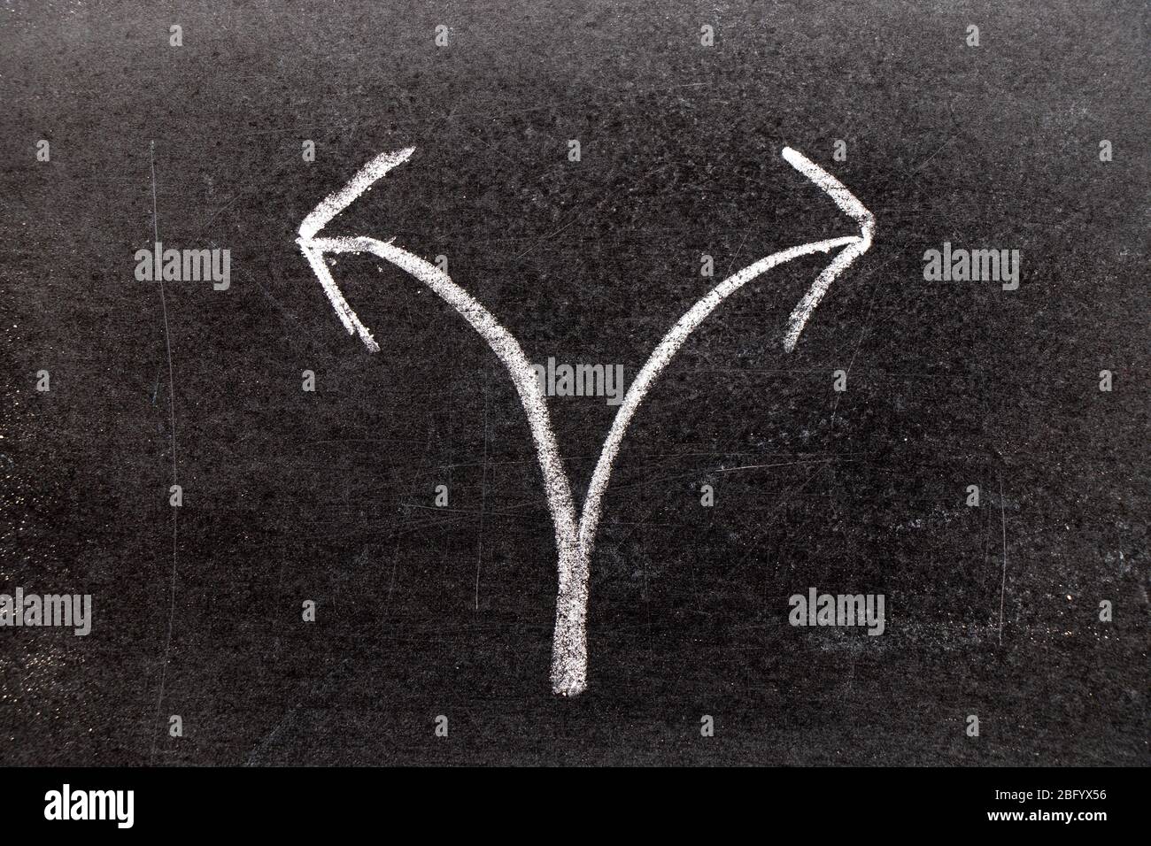 White chalk hand drawing in two way arrow shape on black board ...