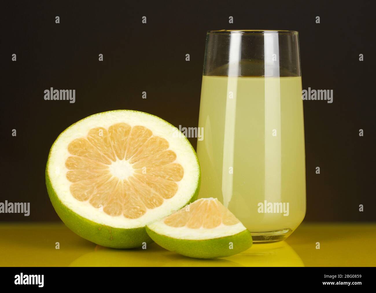 Delicious sweetie juice in glass and sweetie next to it on dark orange ...