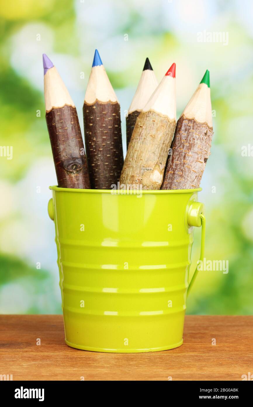 Colorful wooden pencils in pail on wooden table on bright background ...