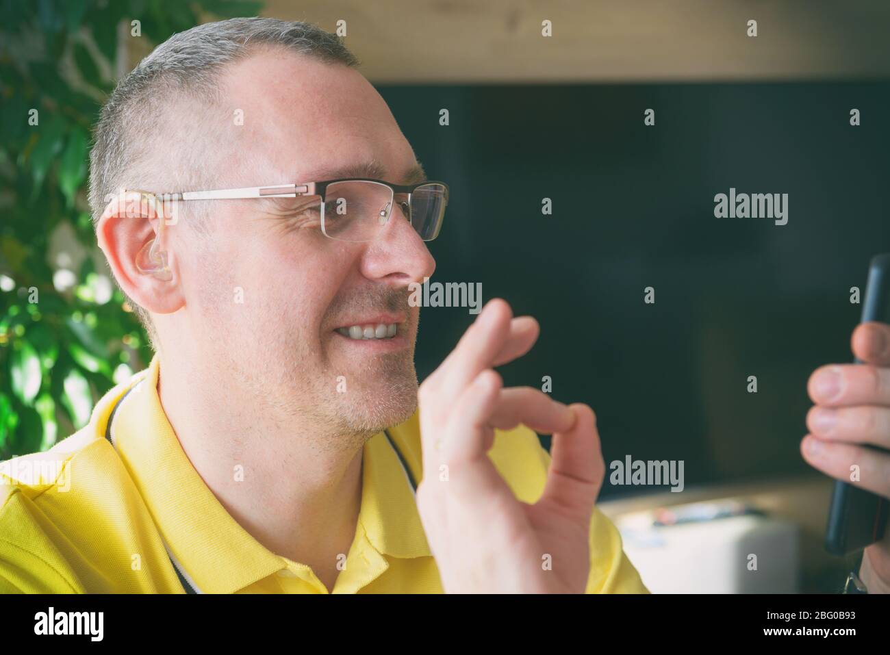 Smiling Deaf man talking using sign language on the smart phone's cam ...