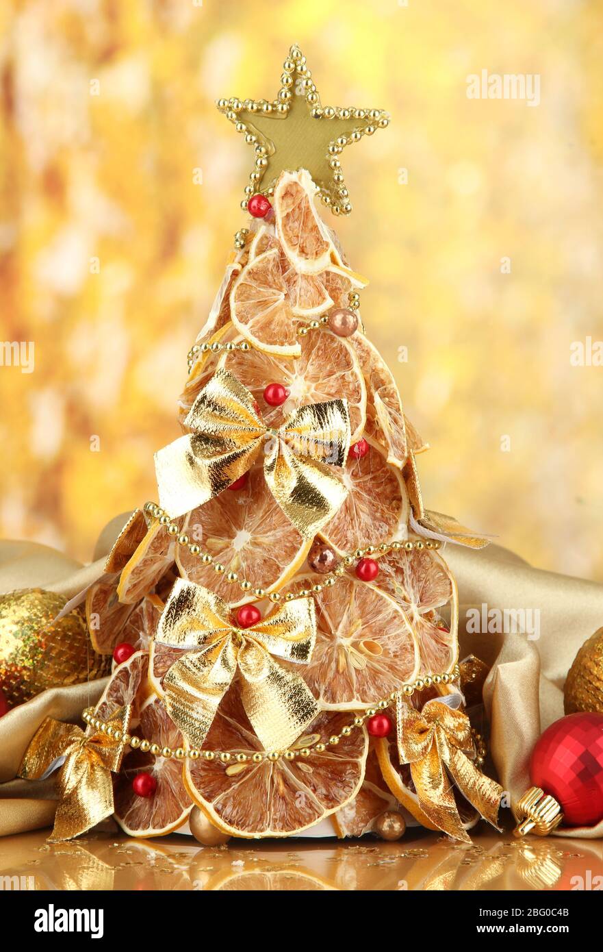 beautiful christmas tree of dry lemons with decor, on yellow background ...