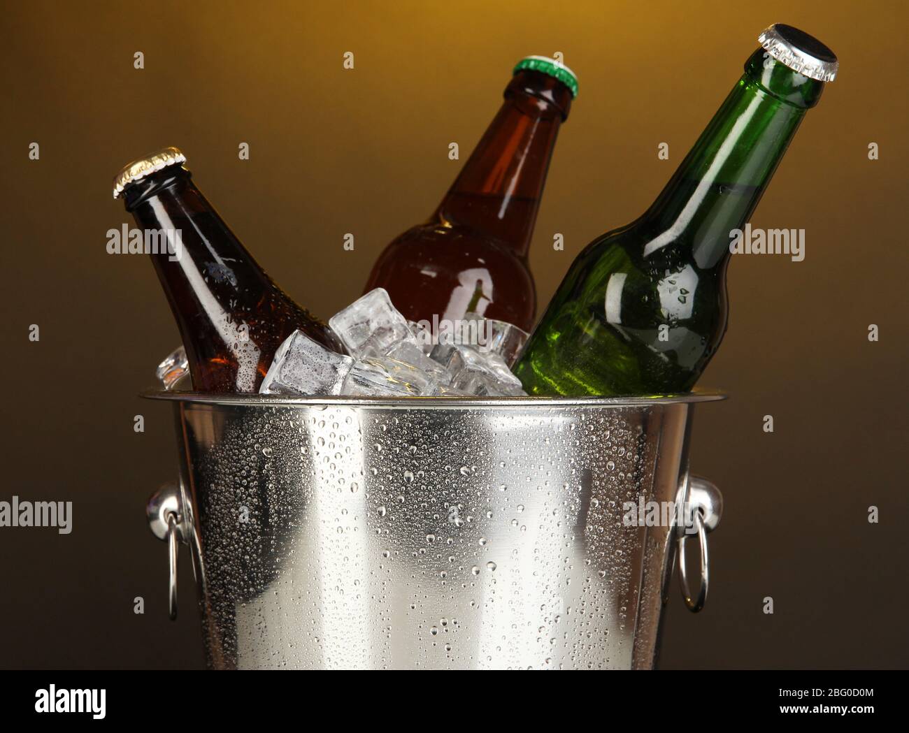 Beer bottles in ice bucket on darck yellow background Stock Photo - Alamy