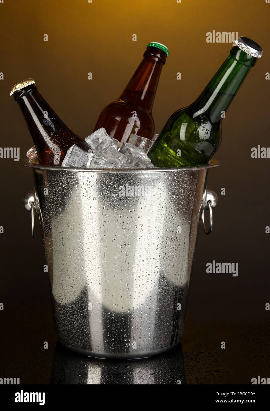 Beer bottles in ice bucket on darck yellow background Stock Photo - Alamy