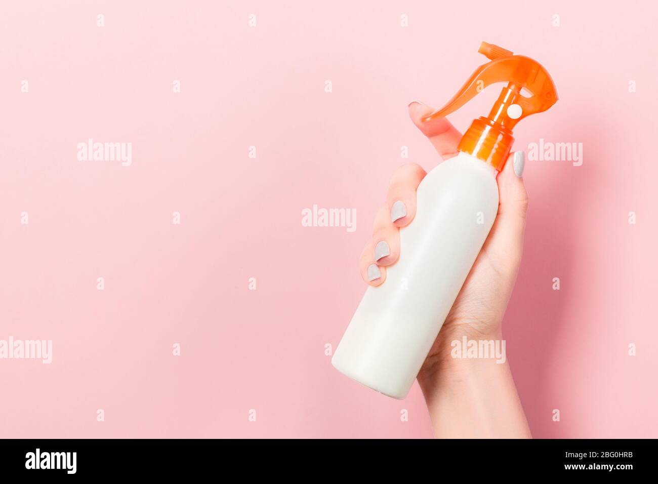 Close up of woman's hand holding a spray of cosmetics product at pink ...