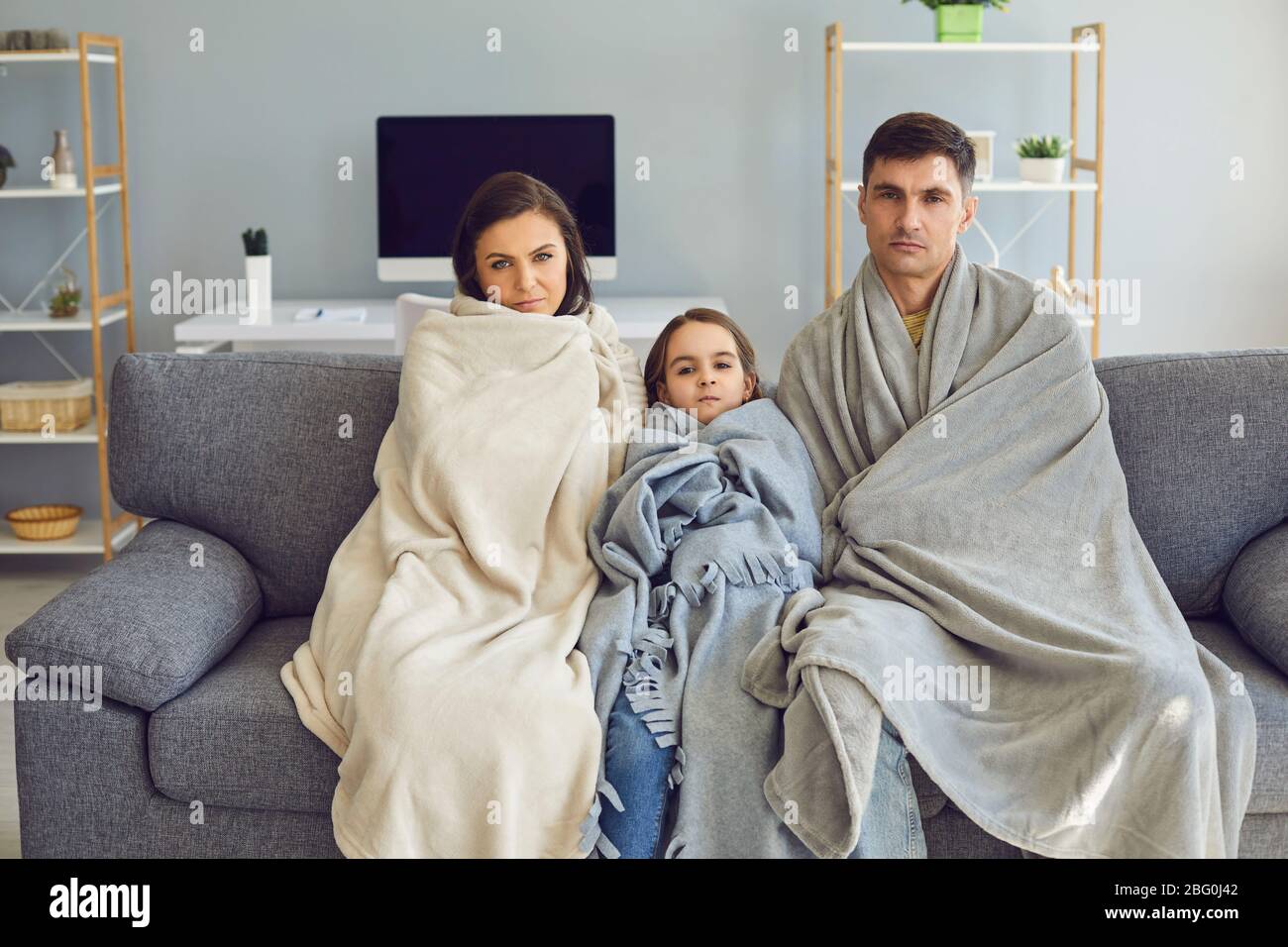 Sick family with a plaid sitting on a sofa looking at the camera with ...