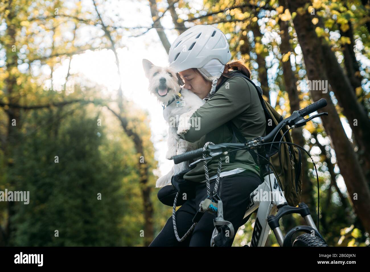 19/4/2020 Asian woman with a bike kissing with a dog in autumn at the ...
