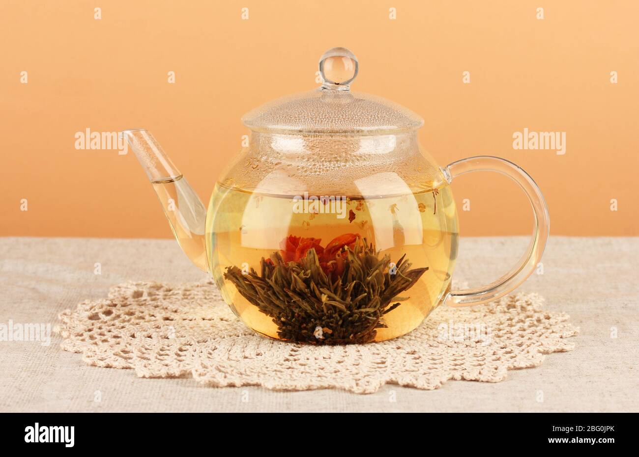 Exotic green tea with flowers in glass teapot on table on color ...