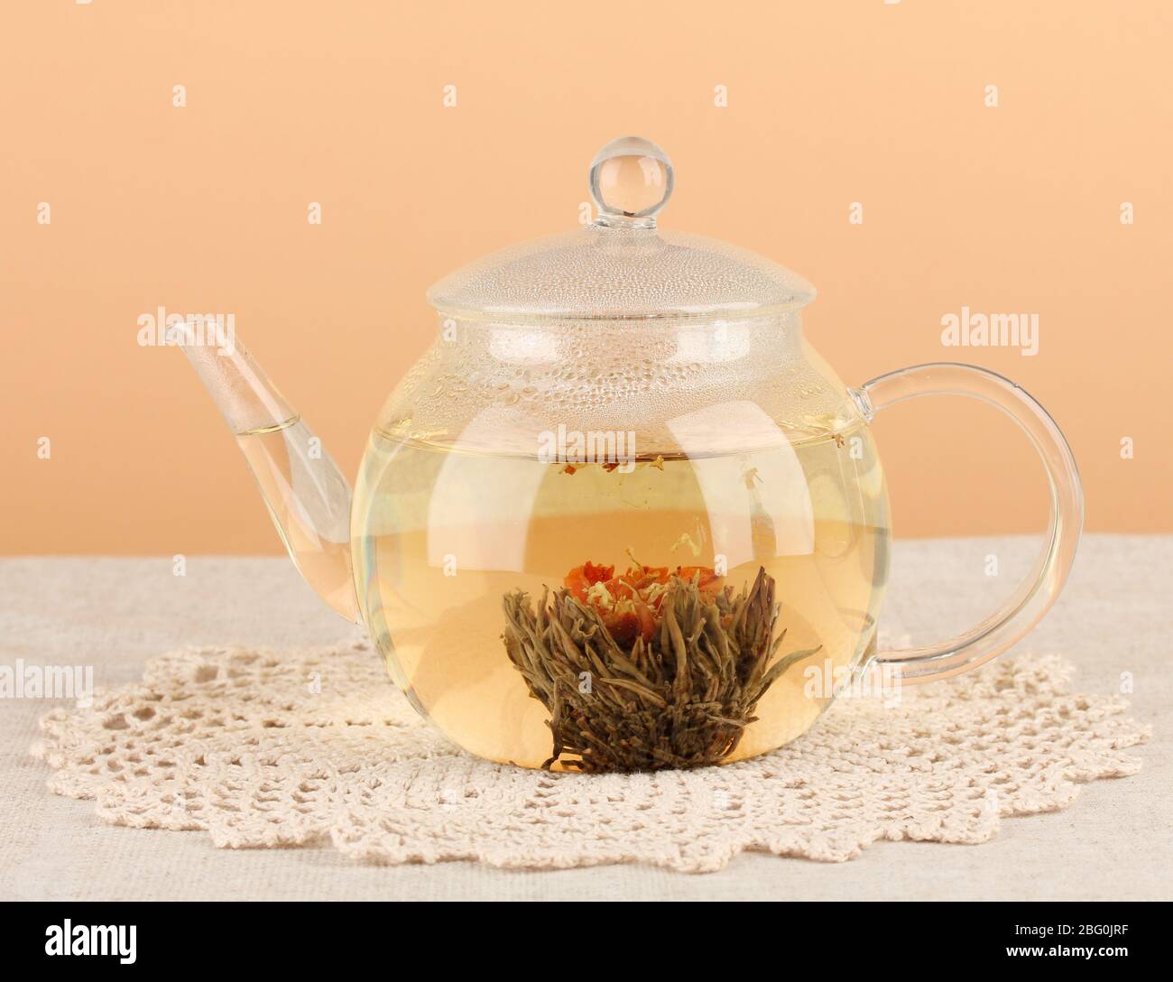 Exotic green tea with flowers in glass teapot on table on color ...