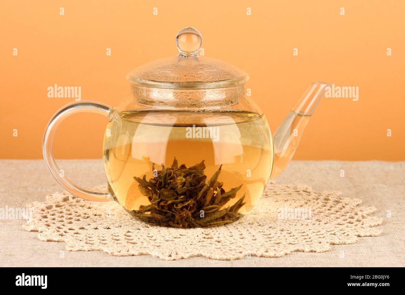Exotic green tea with flowers in glass teapot on table on color ...