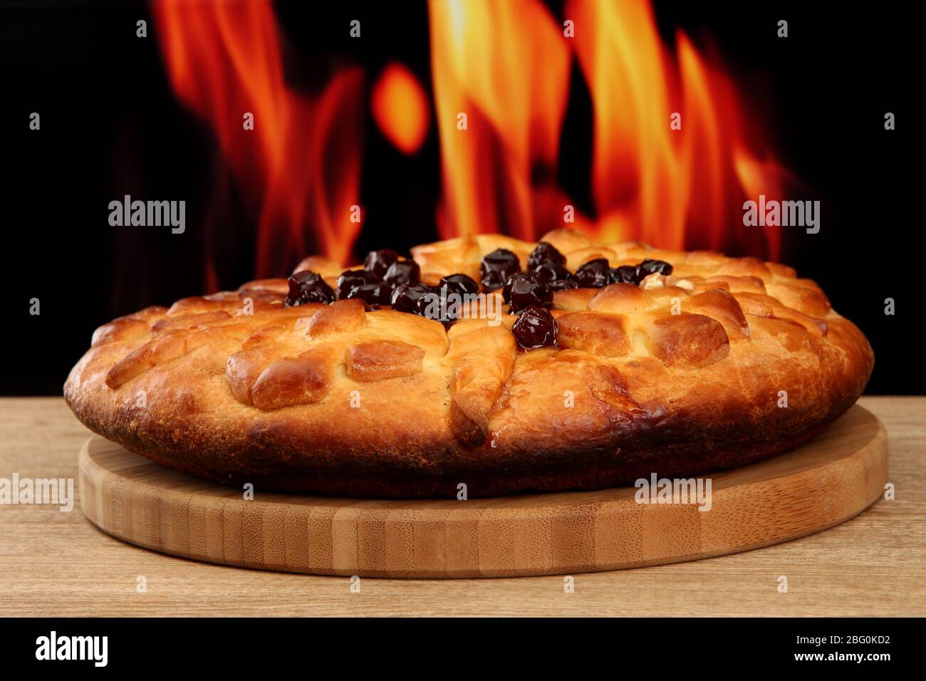 tasty homemade pie with jam, on wooden table on flame background Stock ...