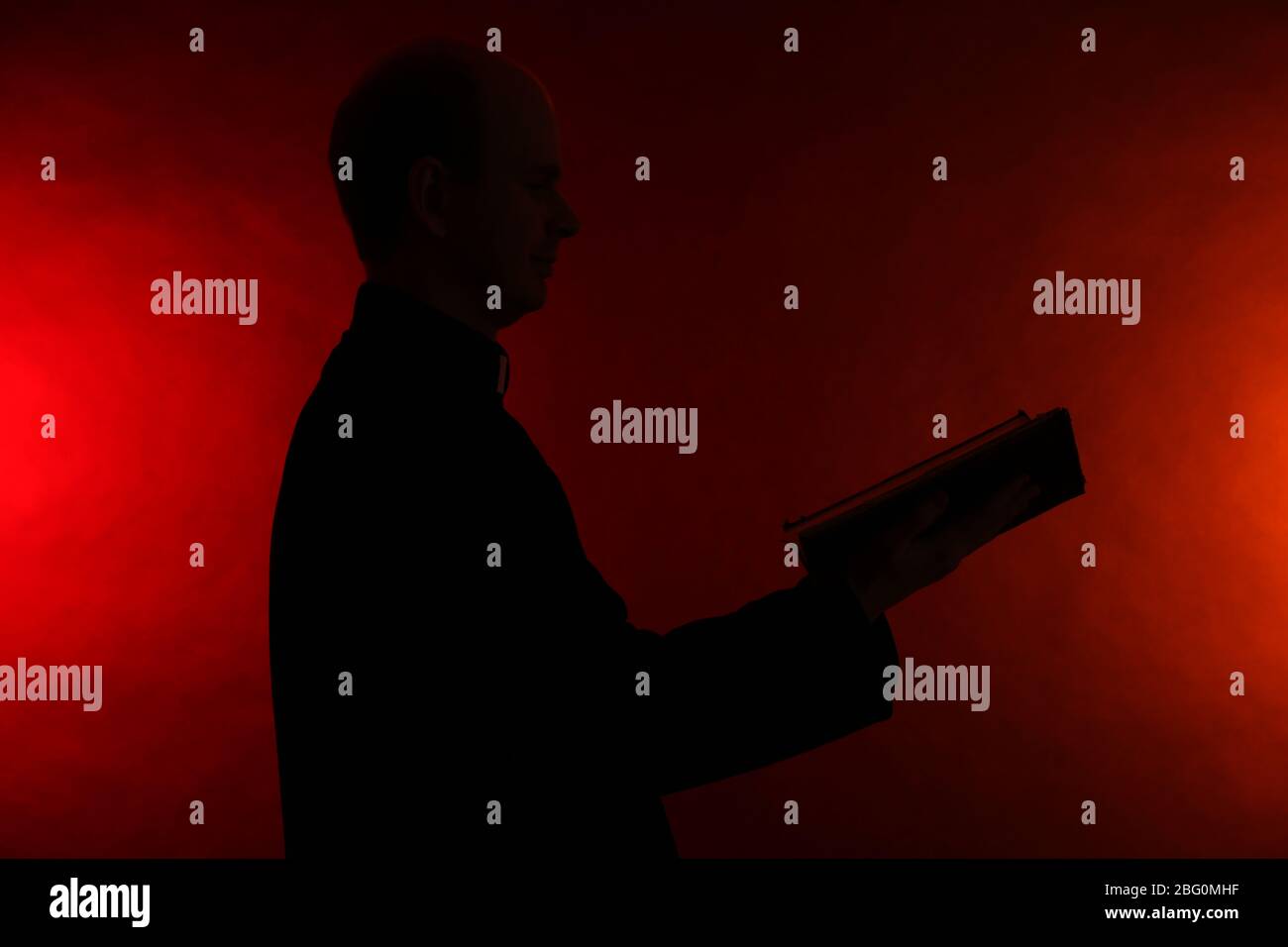 Young pastor with Bible, on dark red background Stock Photo - Alamy