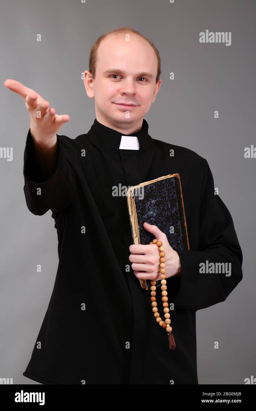 Young pastor with rosary and Bible, on gray background Stock Photo - Alamy