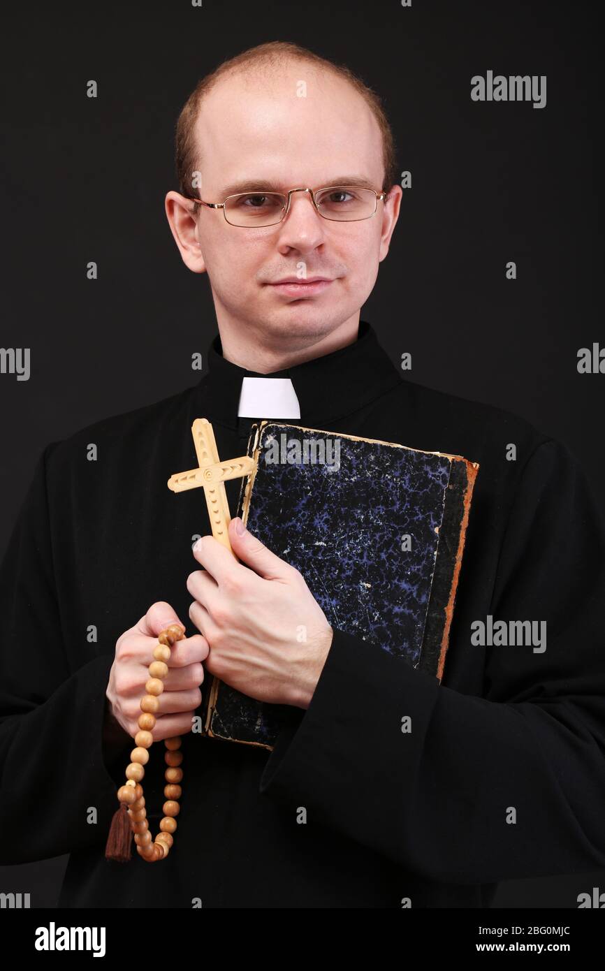 Young pastor with wooden cross and Bible, isolated on black Stock Photo ...
