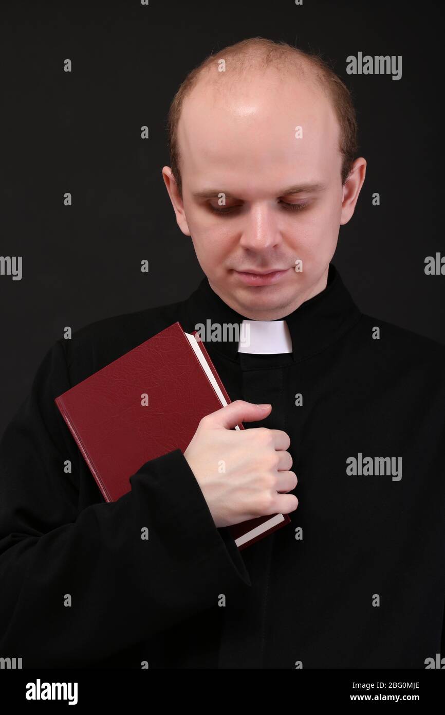 Young pastor with Bible, isolated on black Stock Photo - Alamy
