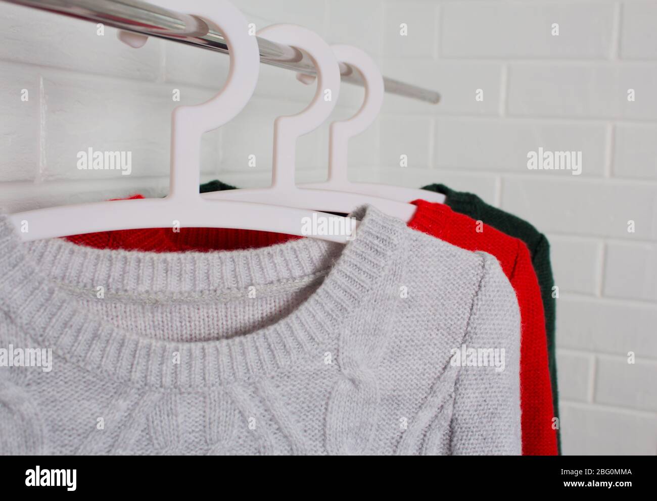 Clothes hang on hangers. Sweaters in red, green and melange colors ...