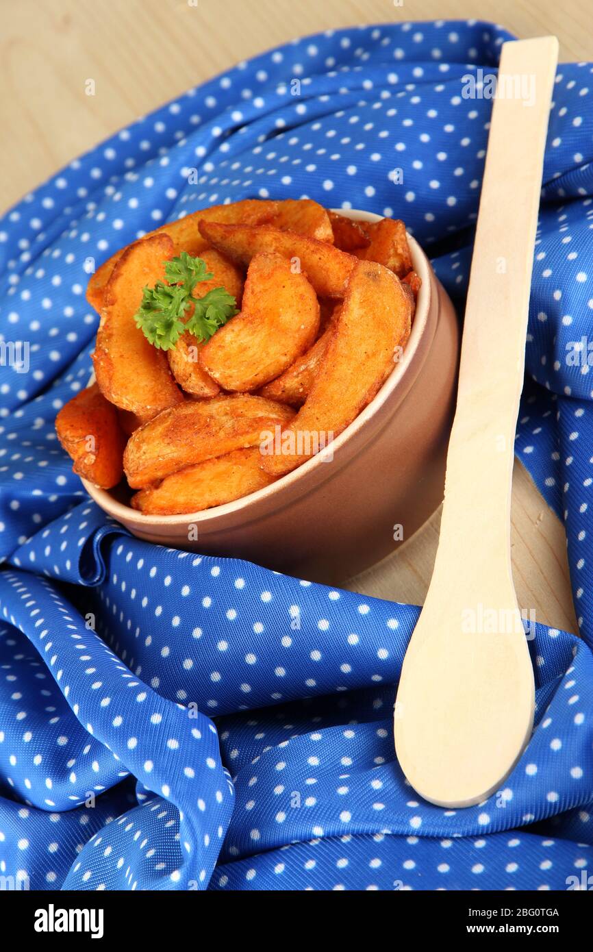 Appetizing village potatoes in bowl on blue fabric close-up Stock Photo ...